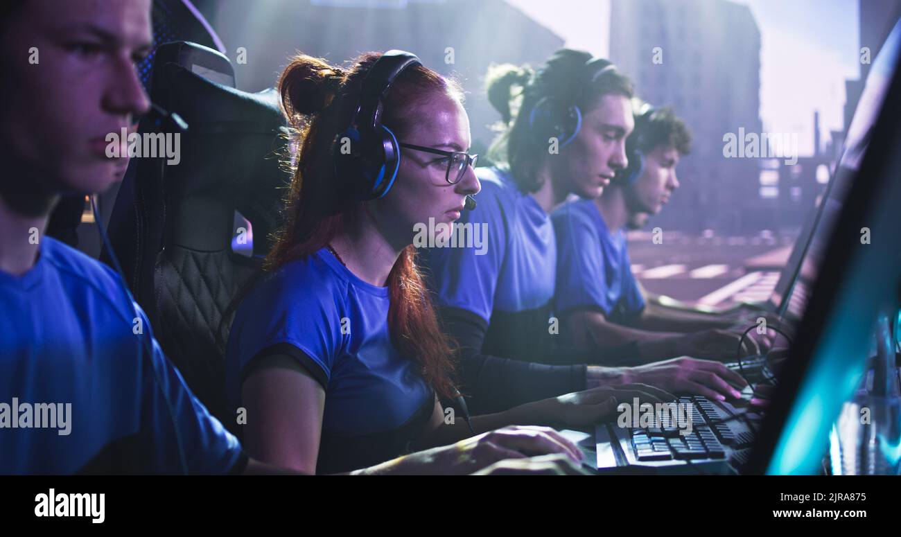 Concentrated young female esportsman gamer in glasses playing shooter ...