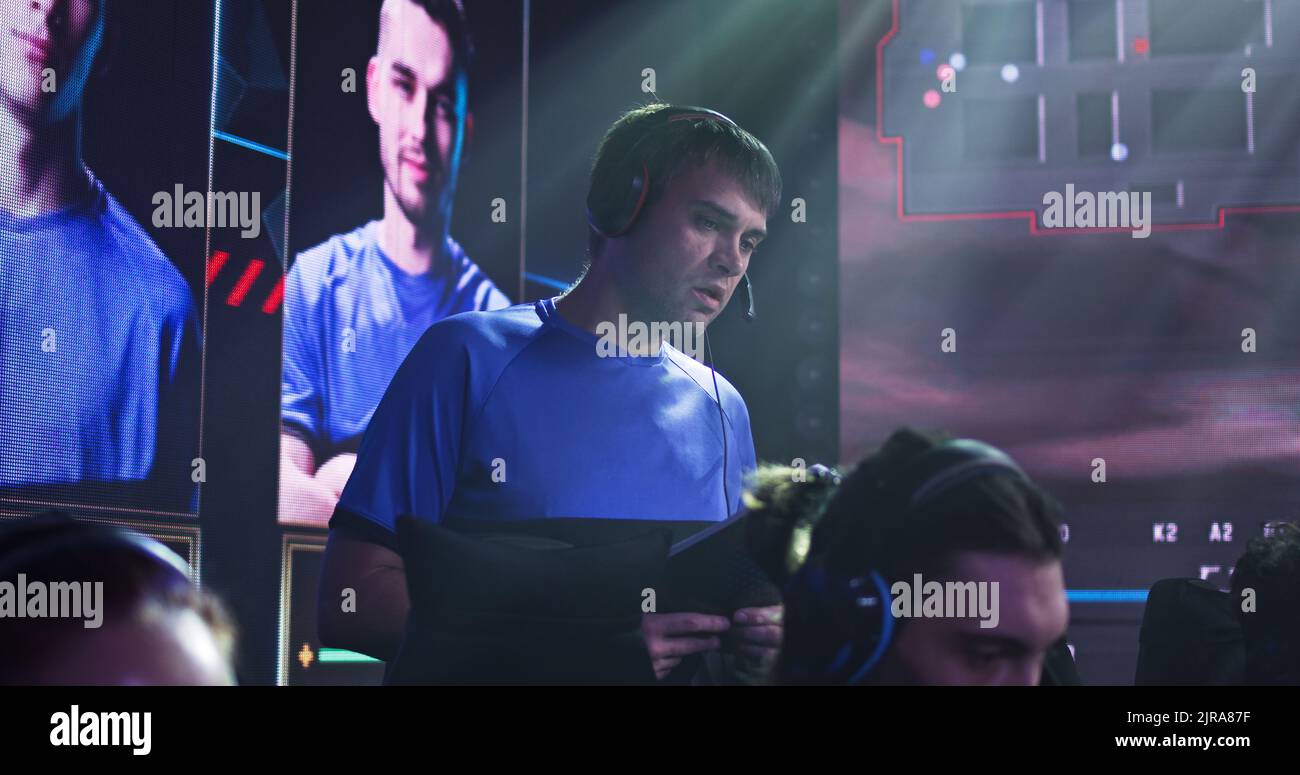 Gamer in headset reading game strategy and speaking to team of cyber ...