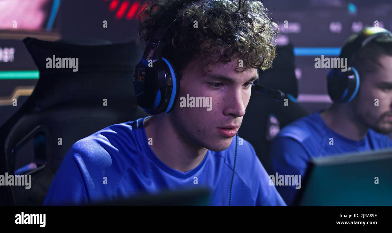 Concentrated esportsman gamer player with curly hair and headphones ...