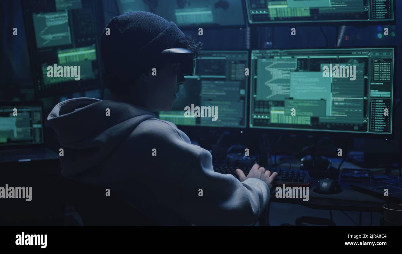Young cybercriminal in augmented reality glasses hacking secret data in ...