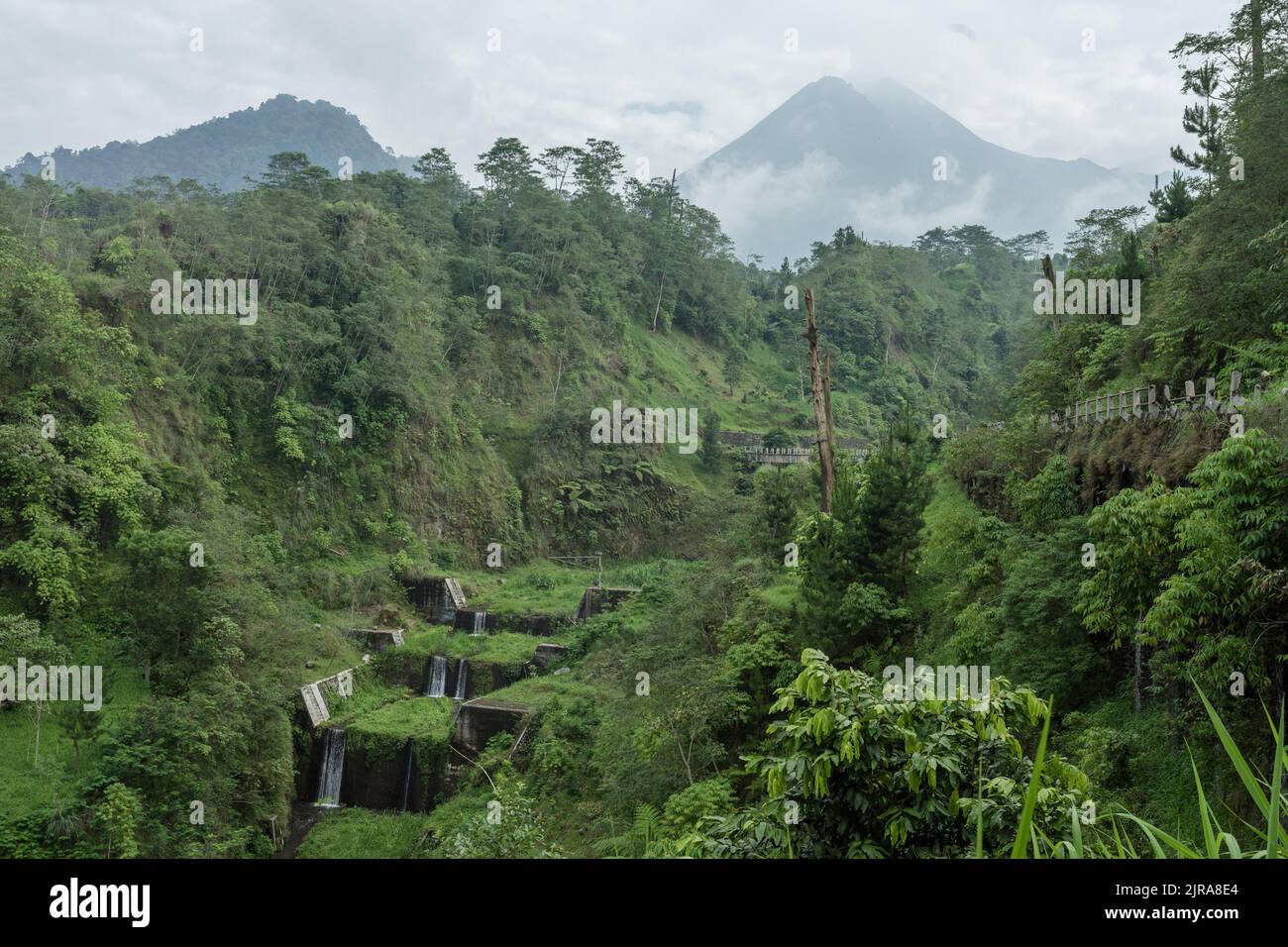 A waterfall and mount Merapi volcano as seen from Plunyon Kalikuning in ...