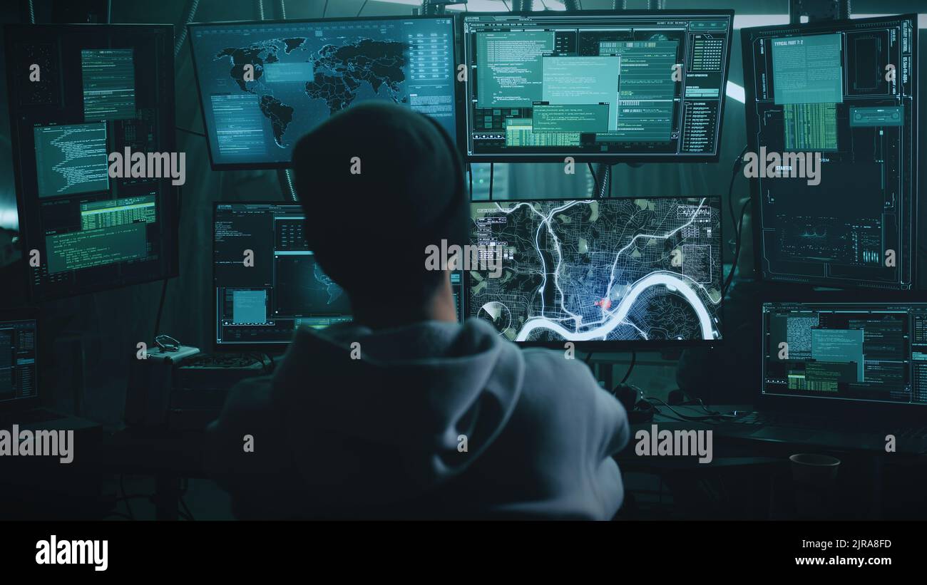 Teenage hacker with glasses watching a car on a monitor and pressing a ...