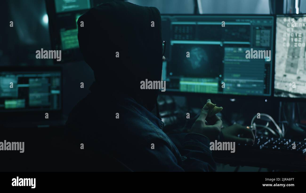 A hacker in glasses at a computer with software, during a cyber attack ...