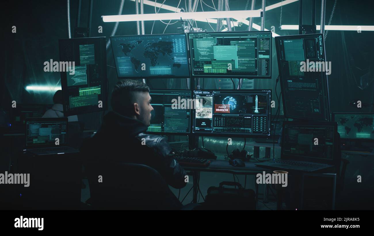 A male hacker in a casual jacket on a chair, hacking a nuclear weapon ...