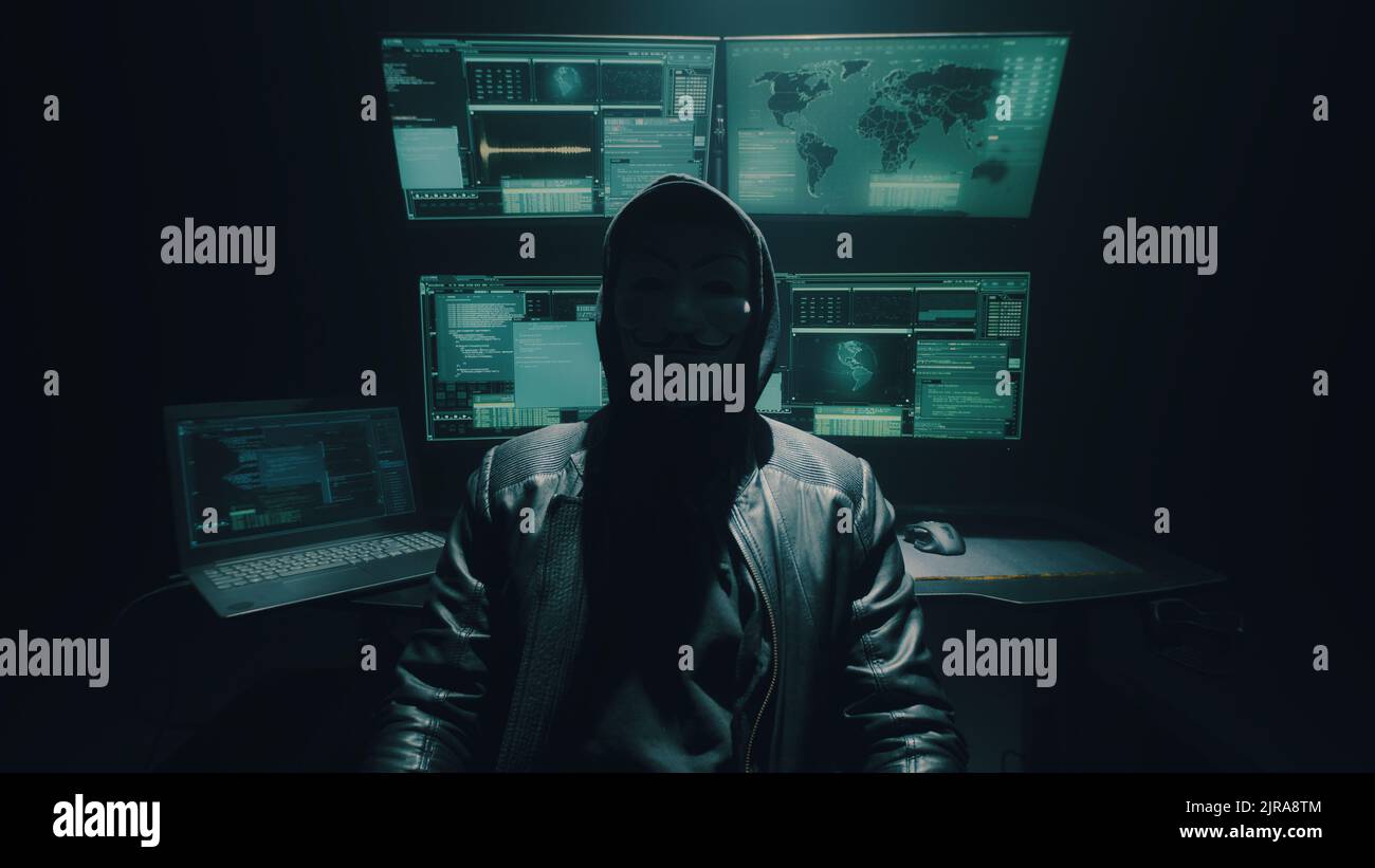 Anonymous man in hoodie sitting on chair near desk with computer ...