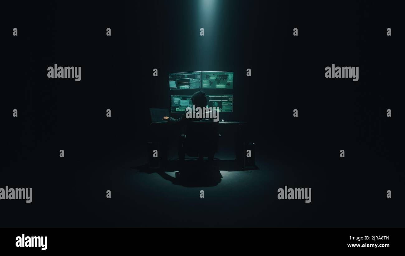 Anonymous hacker in hood cracking secret files on a computer in a dark ...