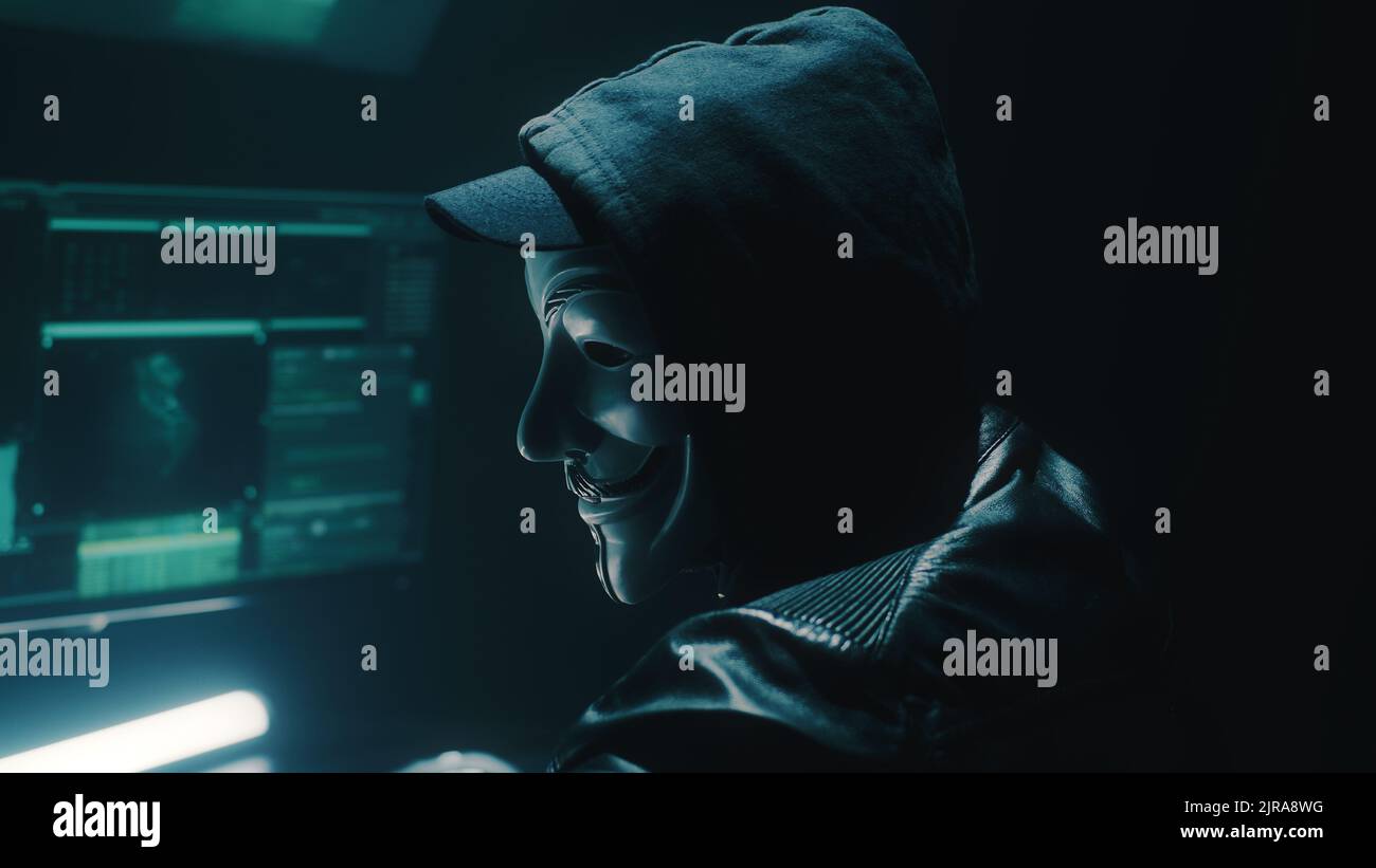 A masked hacker weared black hoodie uses a computer to stage a massive ...