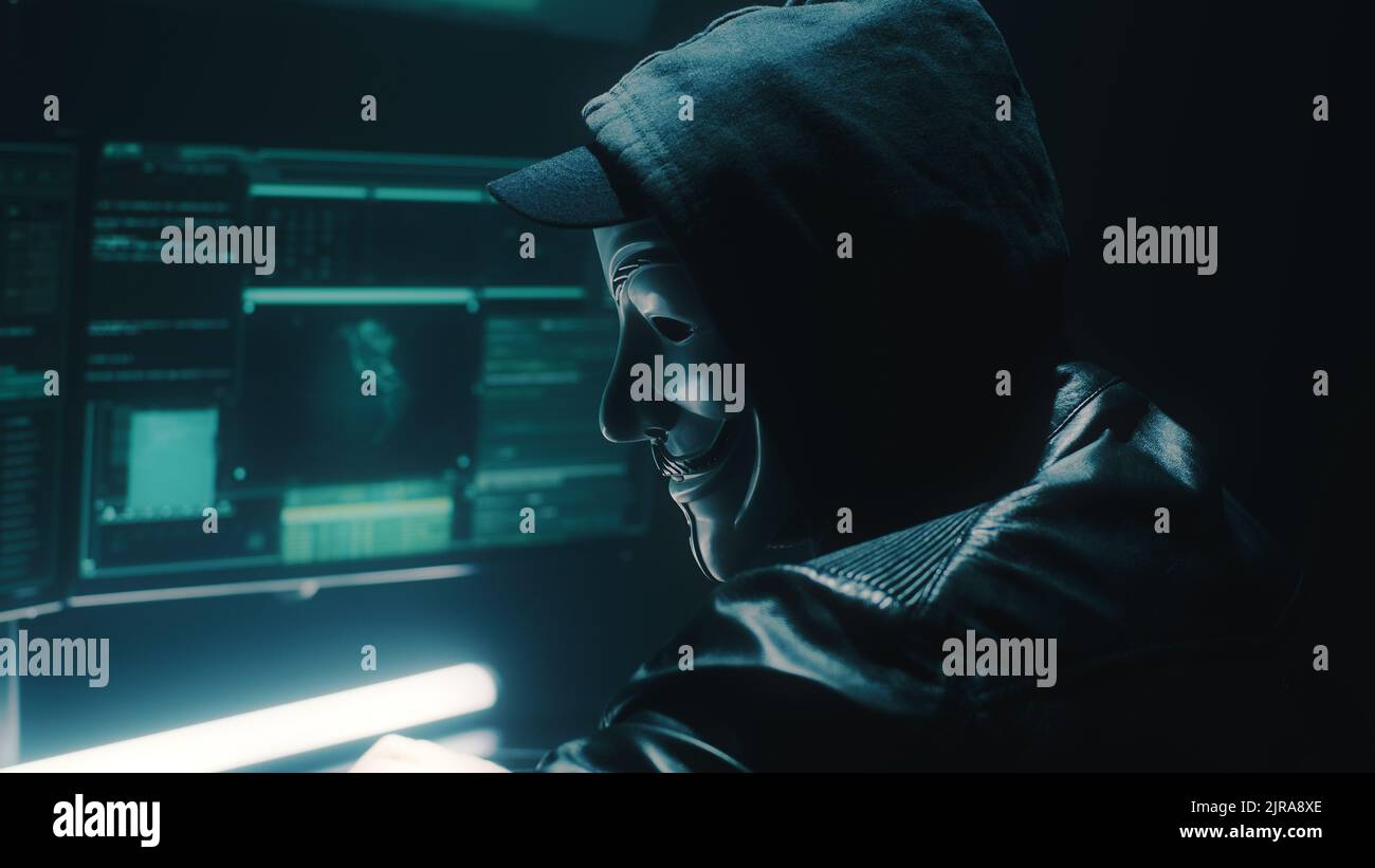 A masked hacker weared black hoodie uses a computer to stage a massive ...