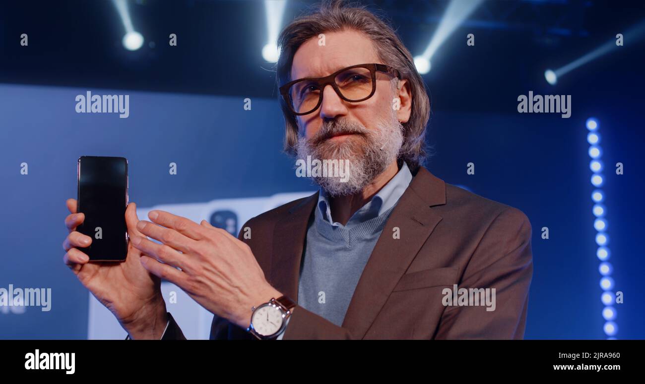 Presenter standing on stage with a new contemporary smartphone at the ...