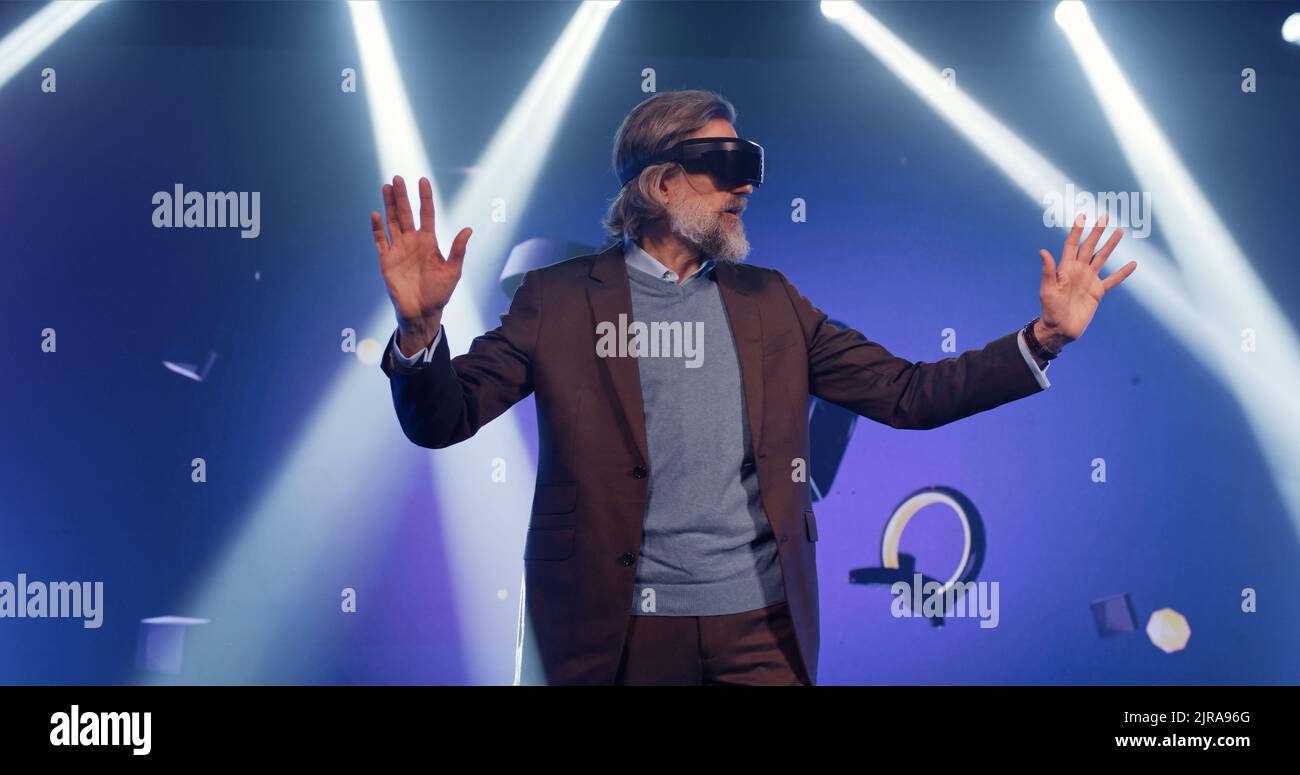 Cheerful male host on stage spreading his arms and showing the audience ...