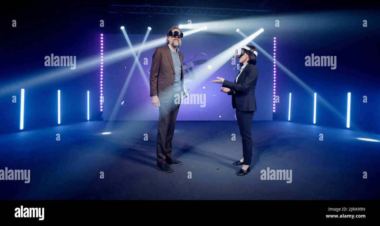 Two presenters in suits on stage trying new augmented reality glasses ...