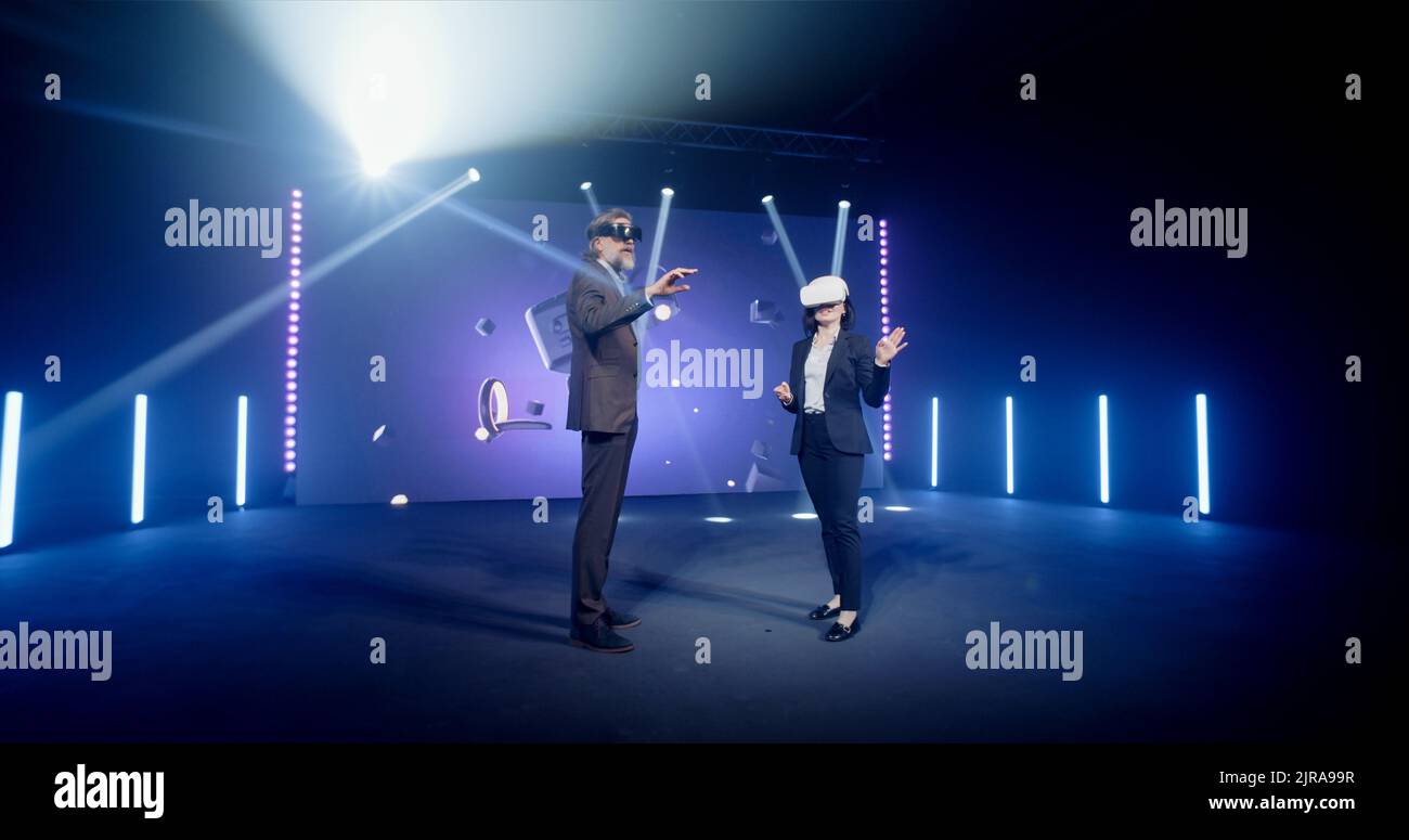 Two presenters in suits on stage trying new augmented reality glasses ...