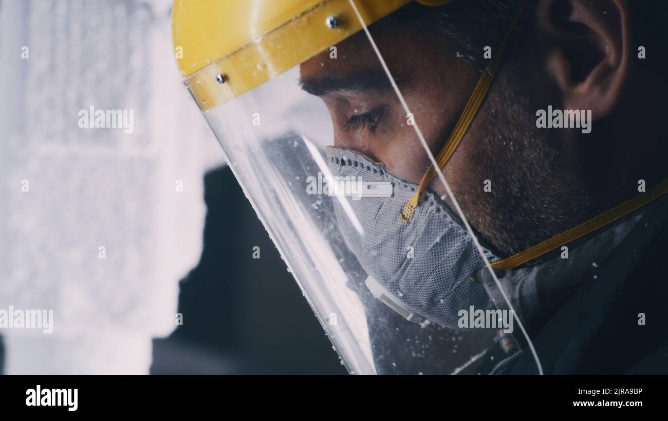 Tilt down view of male artisan in respirator and face mask using remote ...