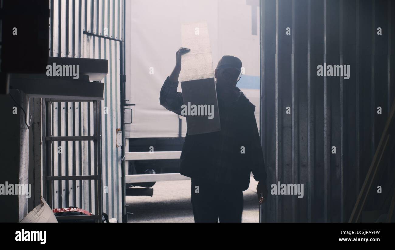 Mature male employee carrying and examining polymer block in dim ...