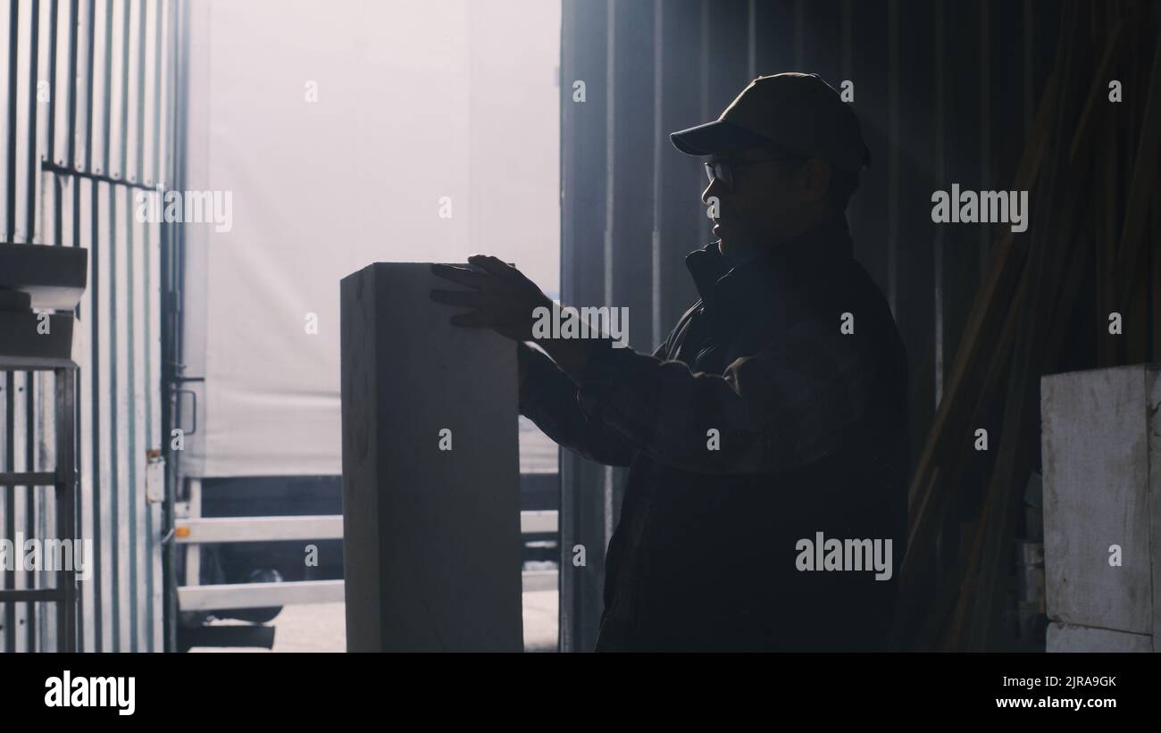 Mature male artisan checking plastic block while standing against ...