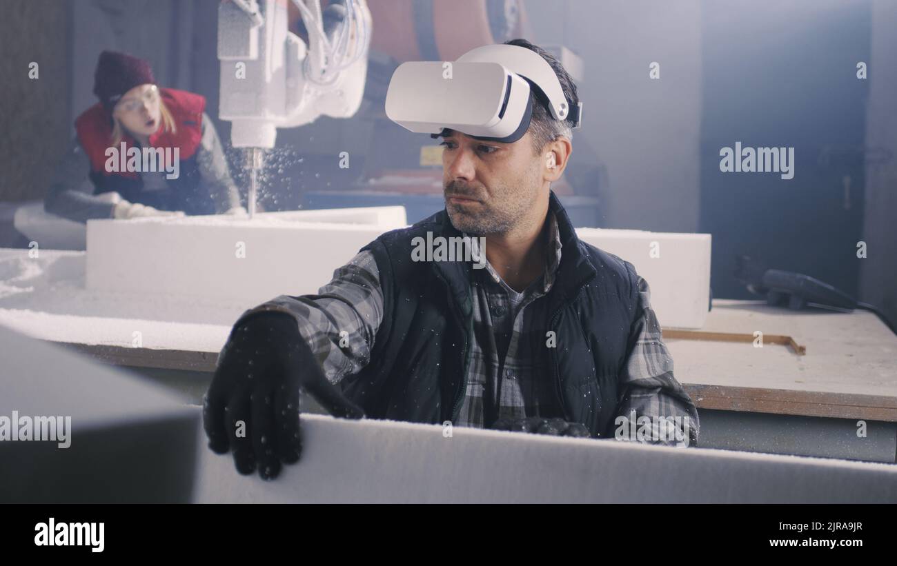 Mature man in contemporary VR headset touching and examining polymer ...