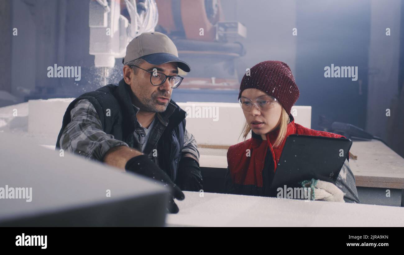 Mature man and young woman with tablet talking about cutting polymer ...