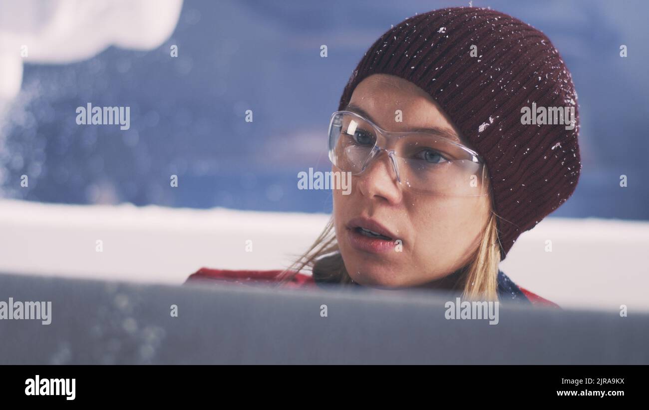 Female employee in hat and goggles removing plastic dust from polymer ...