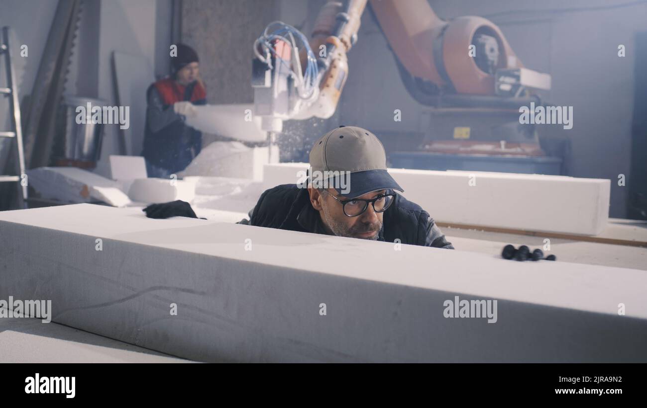 Middle aged male employee in cap and glasses examining and putting ...