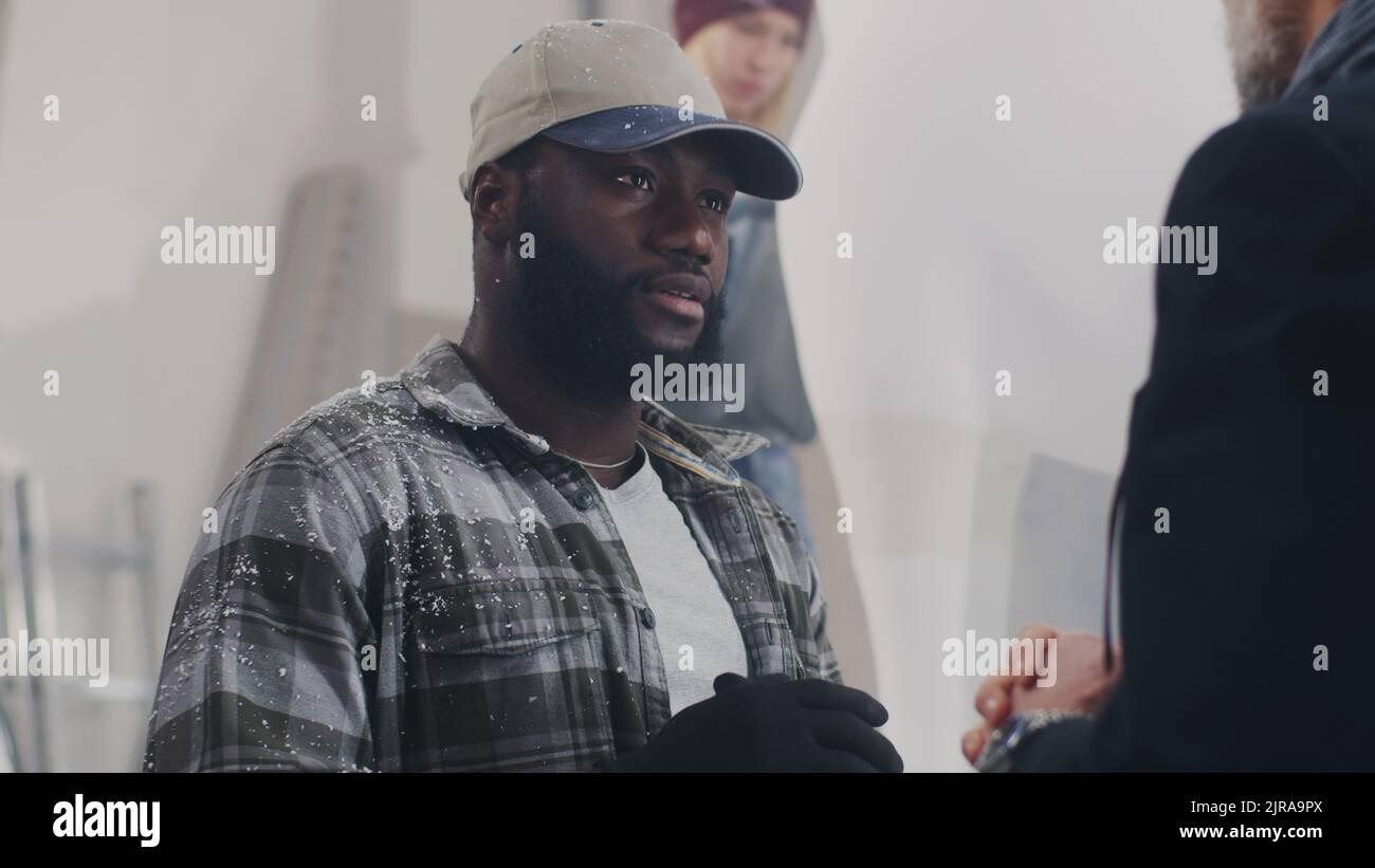 Positive African American male artisan in checkered shirt and cap ...