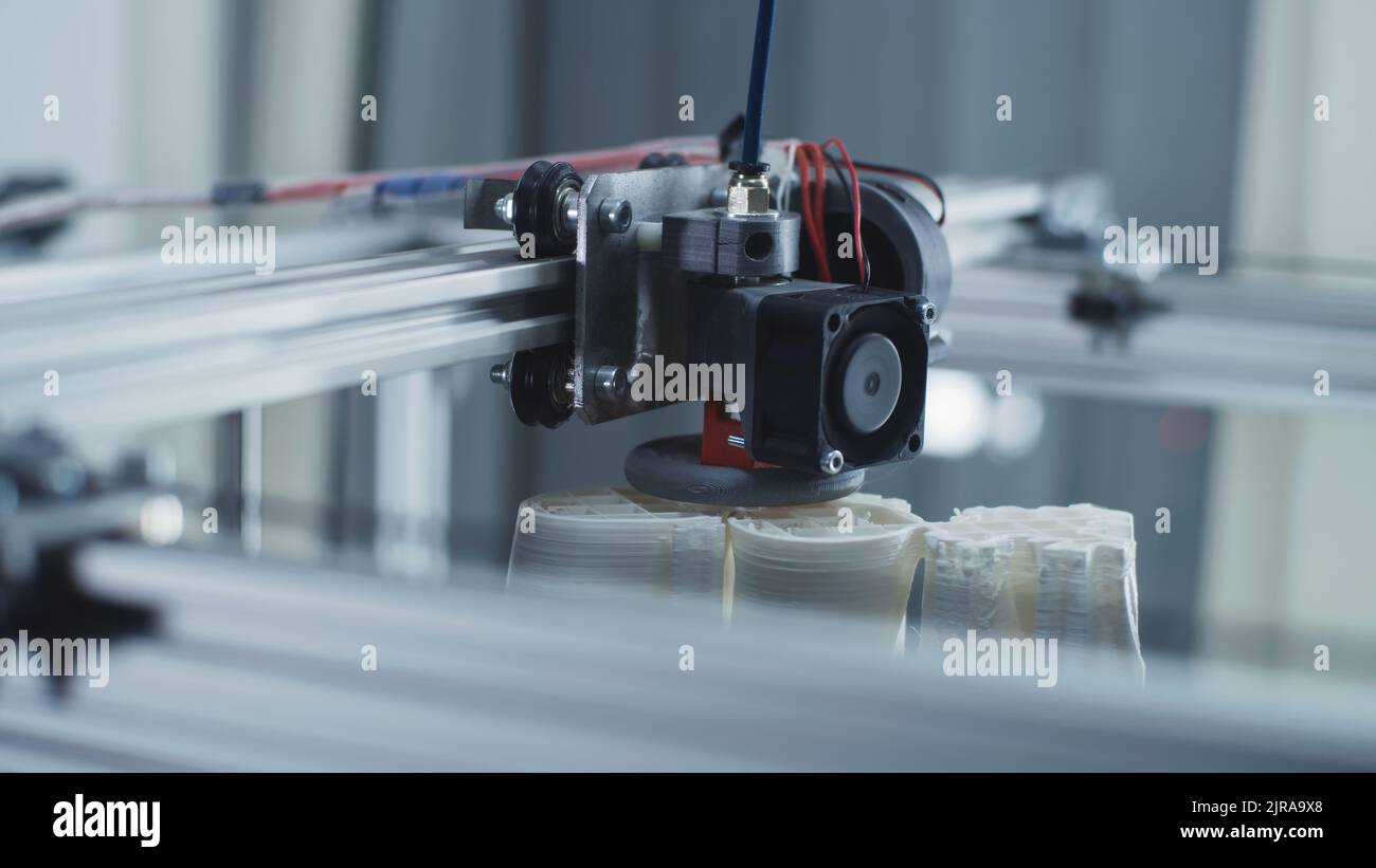 Soft focus of modern 3D printer printing model from white plastic in ...