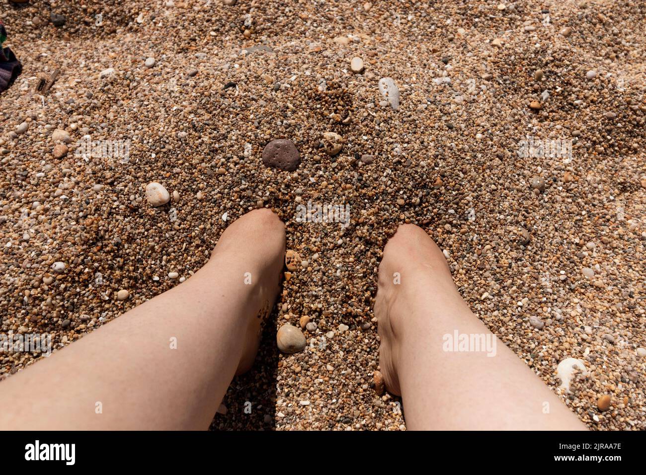 A close up view of a pair of feet buried into the sand-pebbles Stock ...