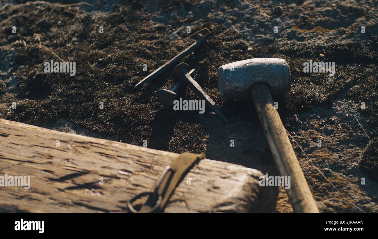 From above hammer and nails placed on ground near weathered cross ...