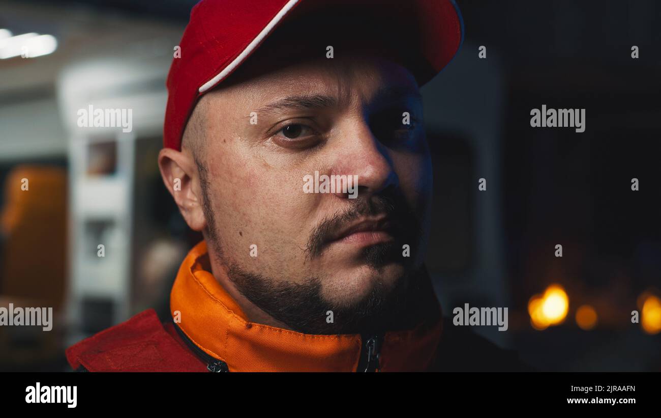 Male paramedic in uniform and hat looking at camera while standing near ...