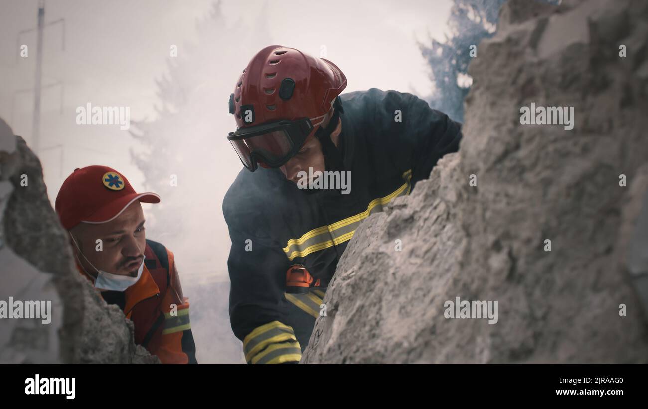 Diverse men in protective uniform inspecting and discussing remains of ...