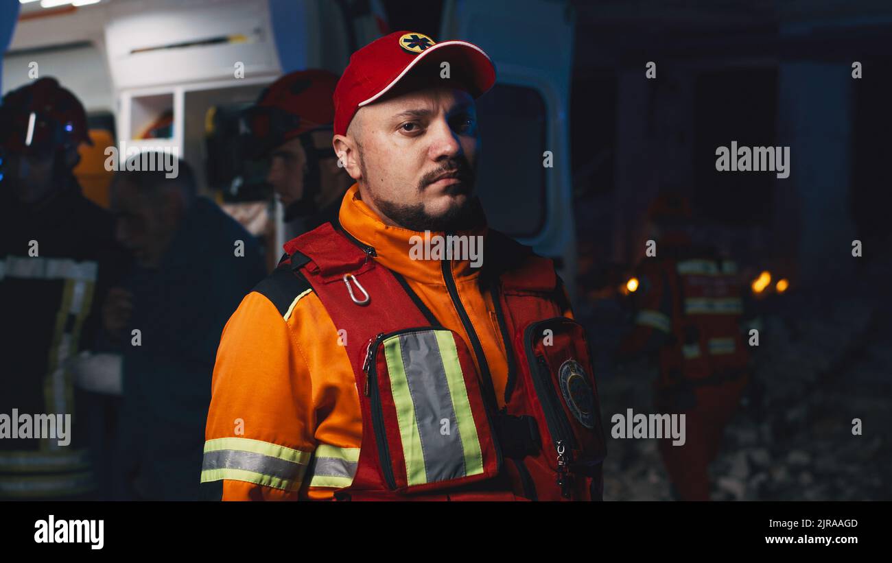 Male paramedic in uniform and hat looking at camera while standing near ...
