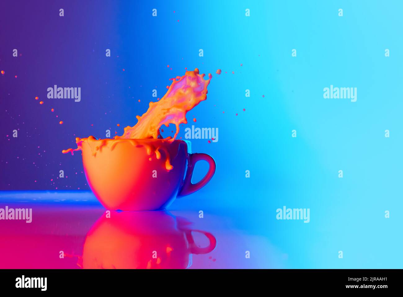 Huge milk splashes. Cup of coffee with milk standing on mirror surface ...