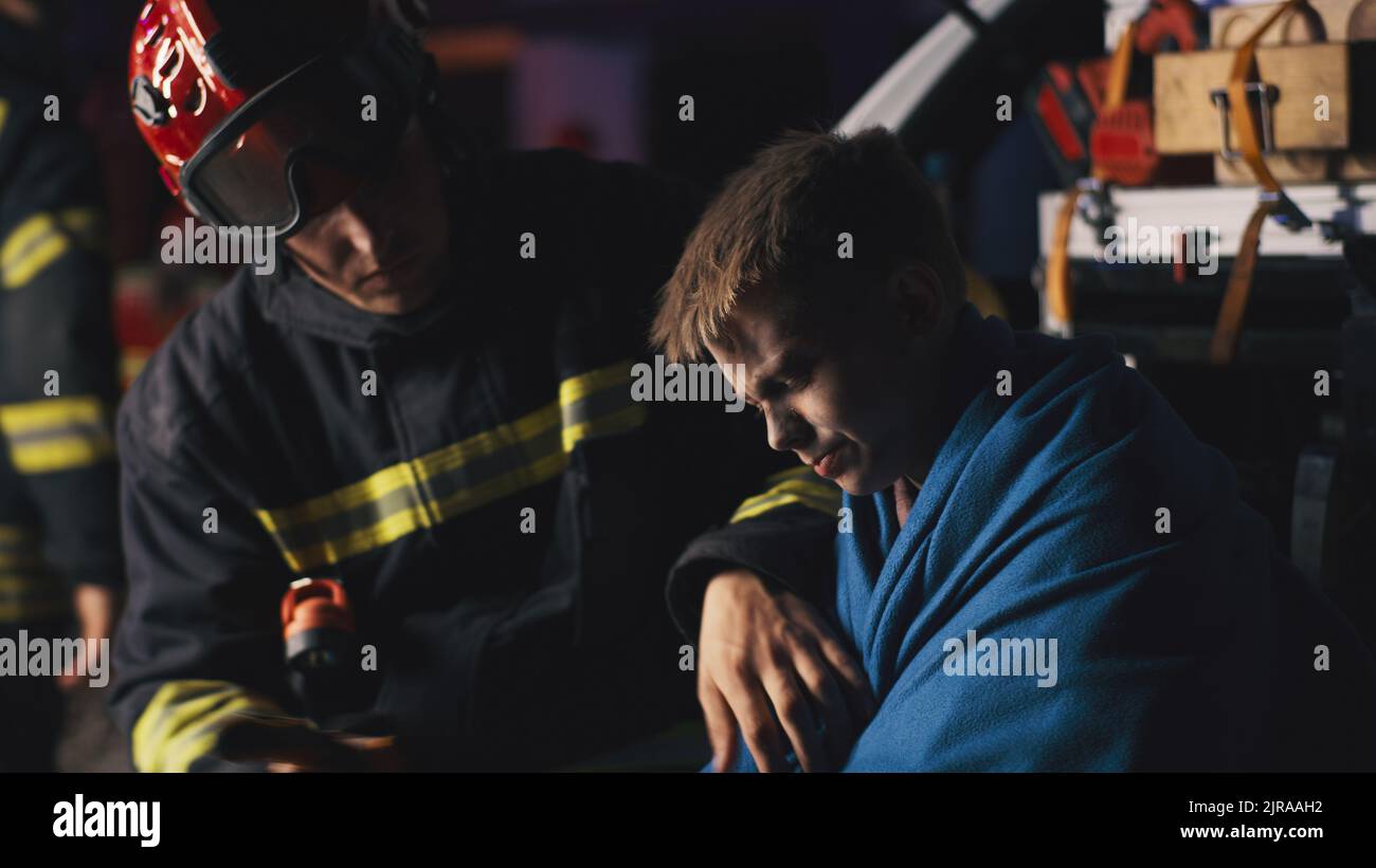 Male emergency service worker asking questions to survivor while ...