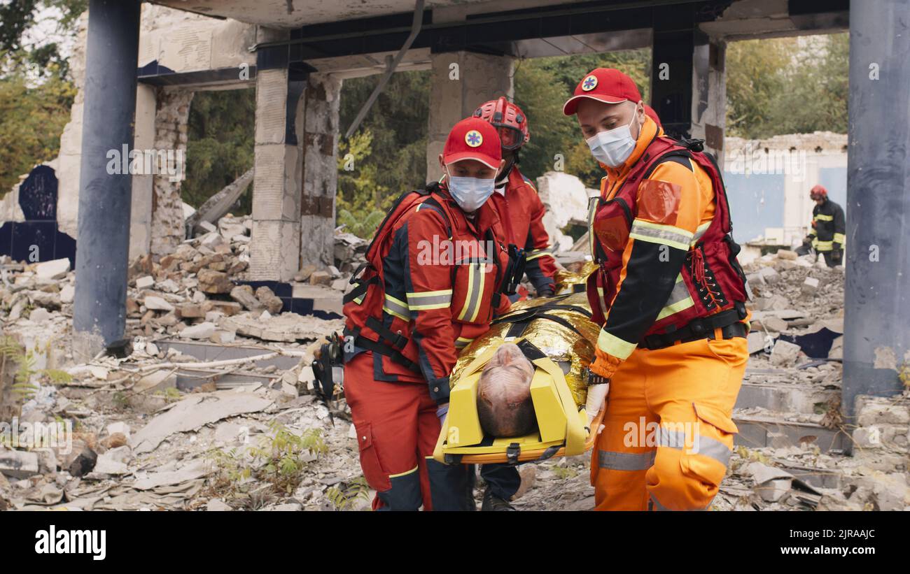 Tracking shot of multiracial men in paramedic uniform carrying survival ...
