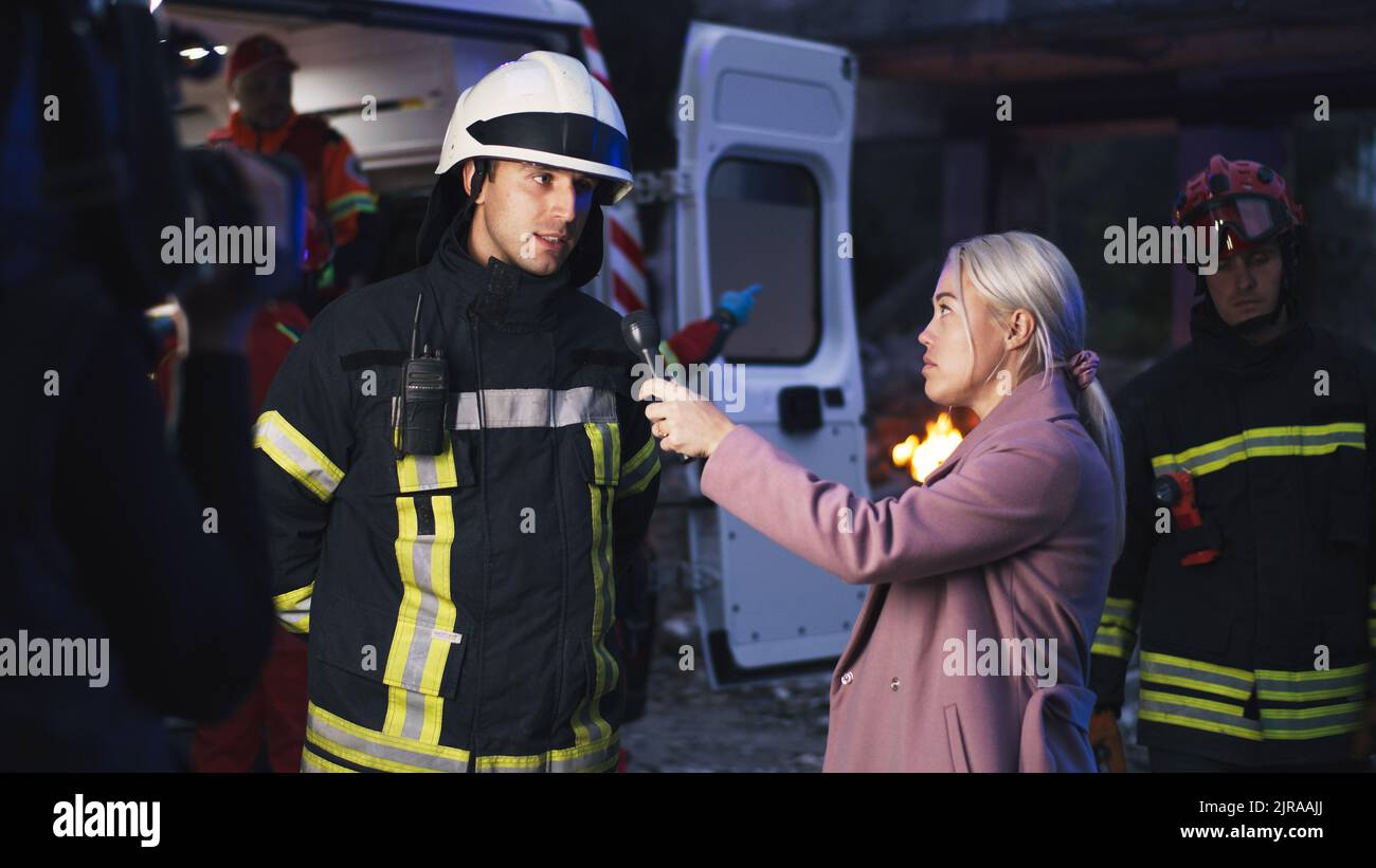 Blond woman asking questions to male emergency worker in front of ...