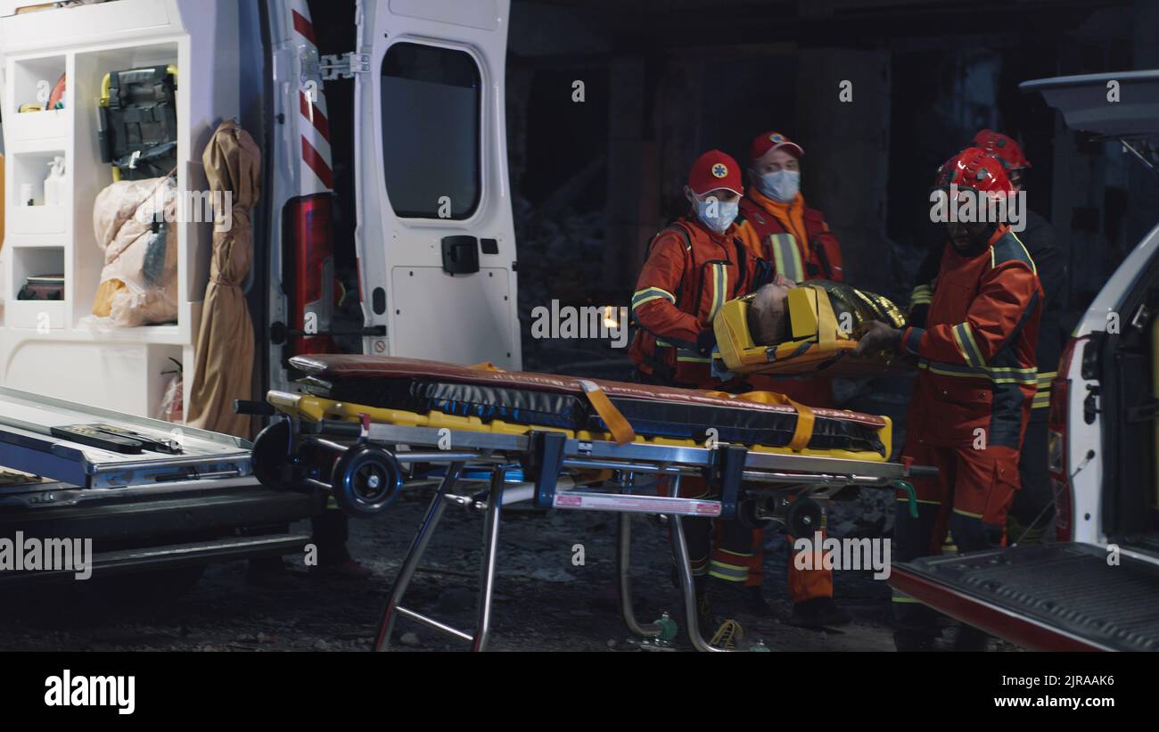Team of diverse paramedics in masks loading carrier with patient into ...