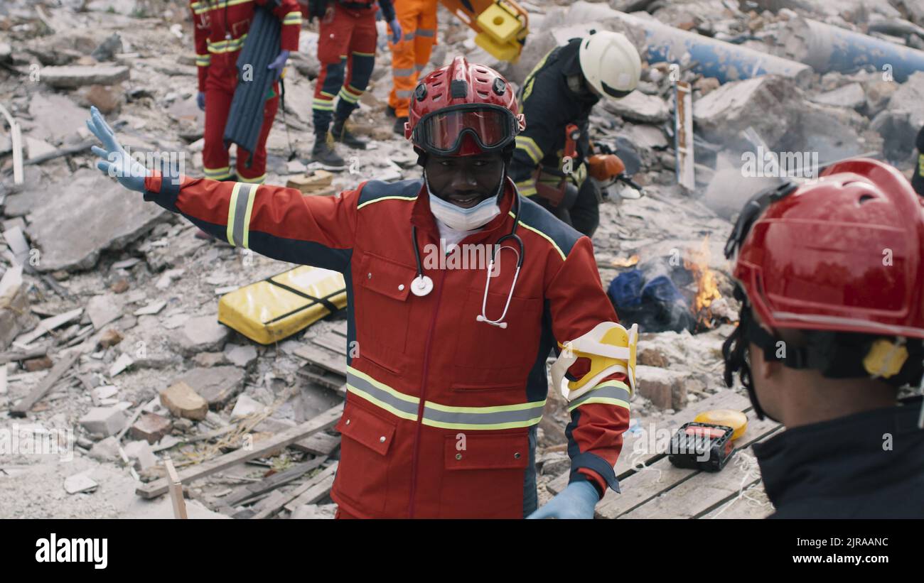 African American man in red uniform pointing away and talking with ...