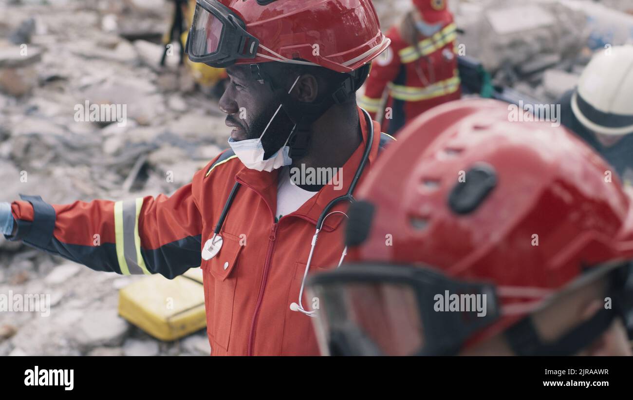 African American male paramedic in red uniform and hardhat pointing ...