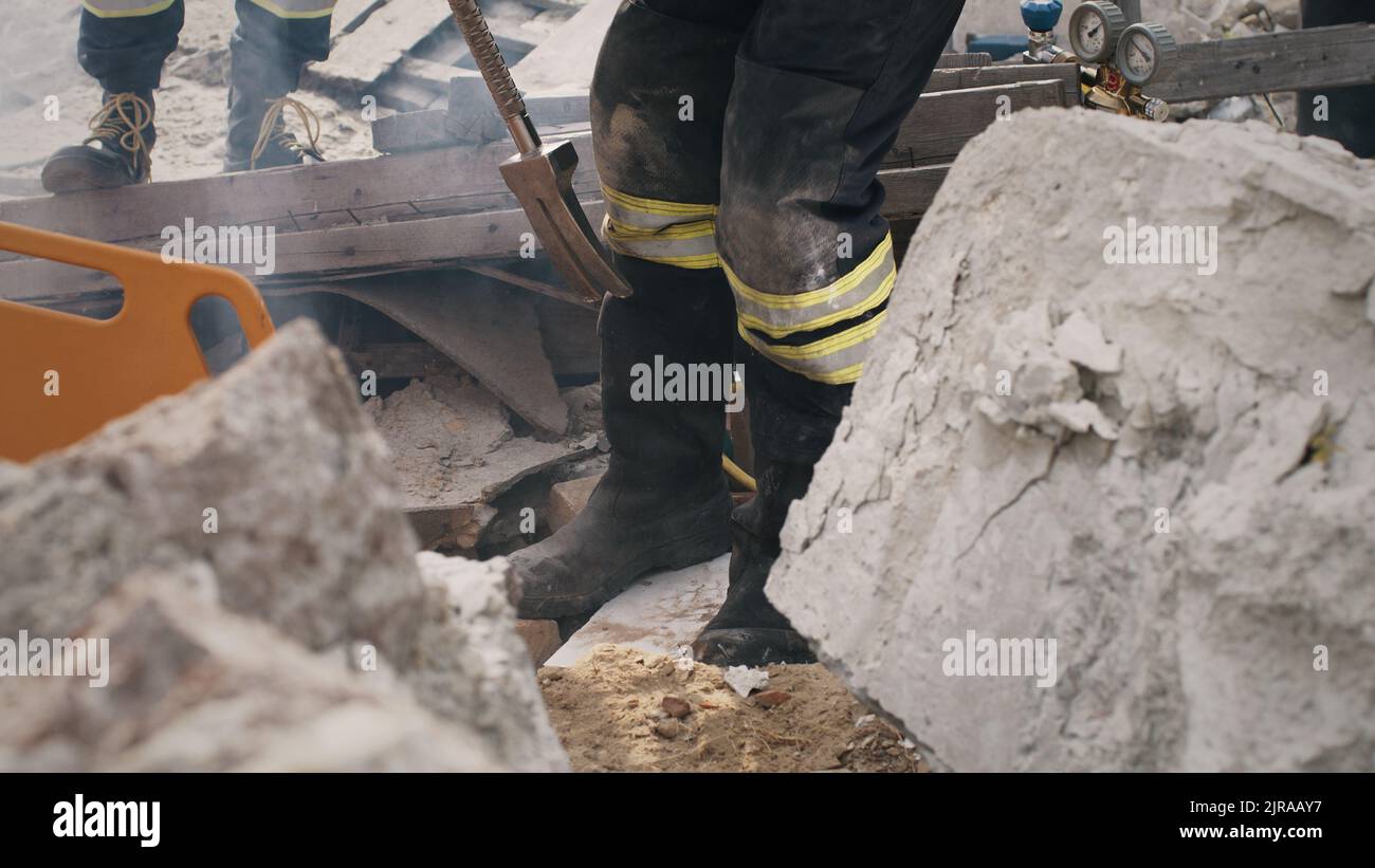 Male emergency service worker digging rubble near paramedics with ...