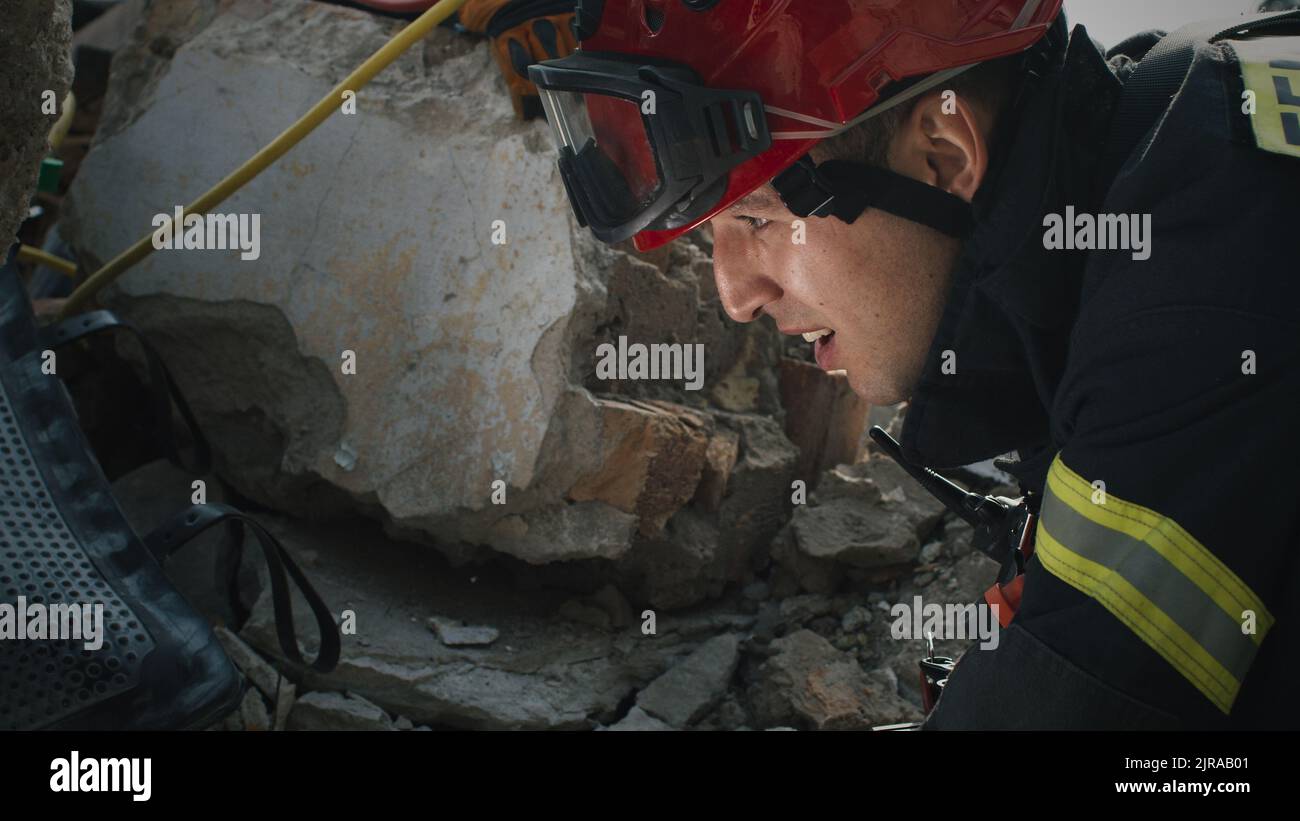 Men in protective uniform and hardhat inspecting remains of demolished ...