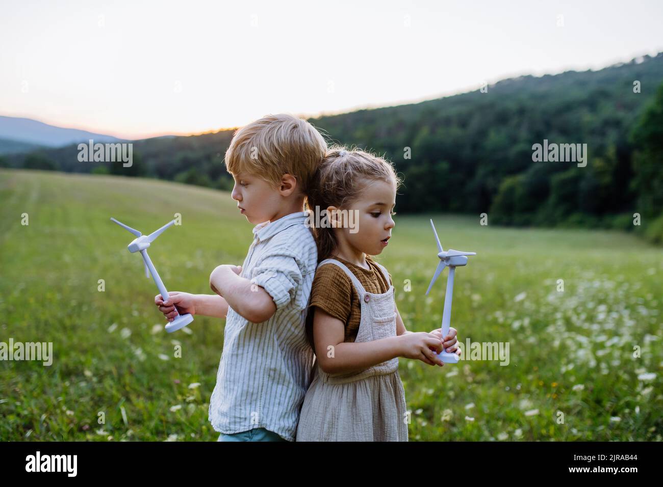 Little children standing in nature with model of wind turbine. Concept ...