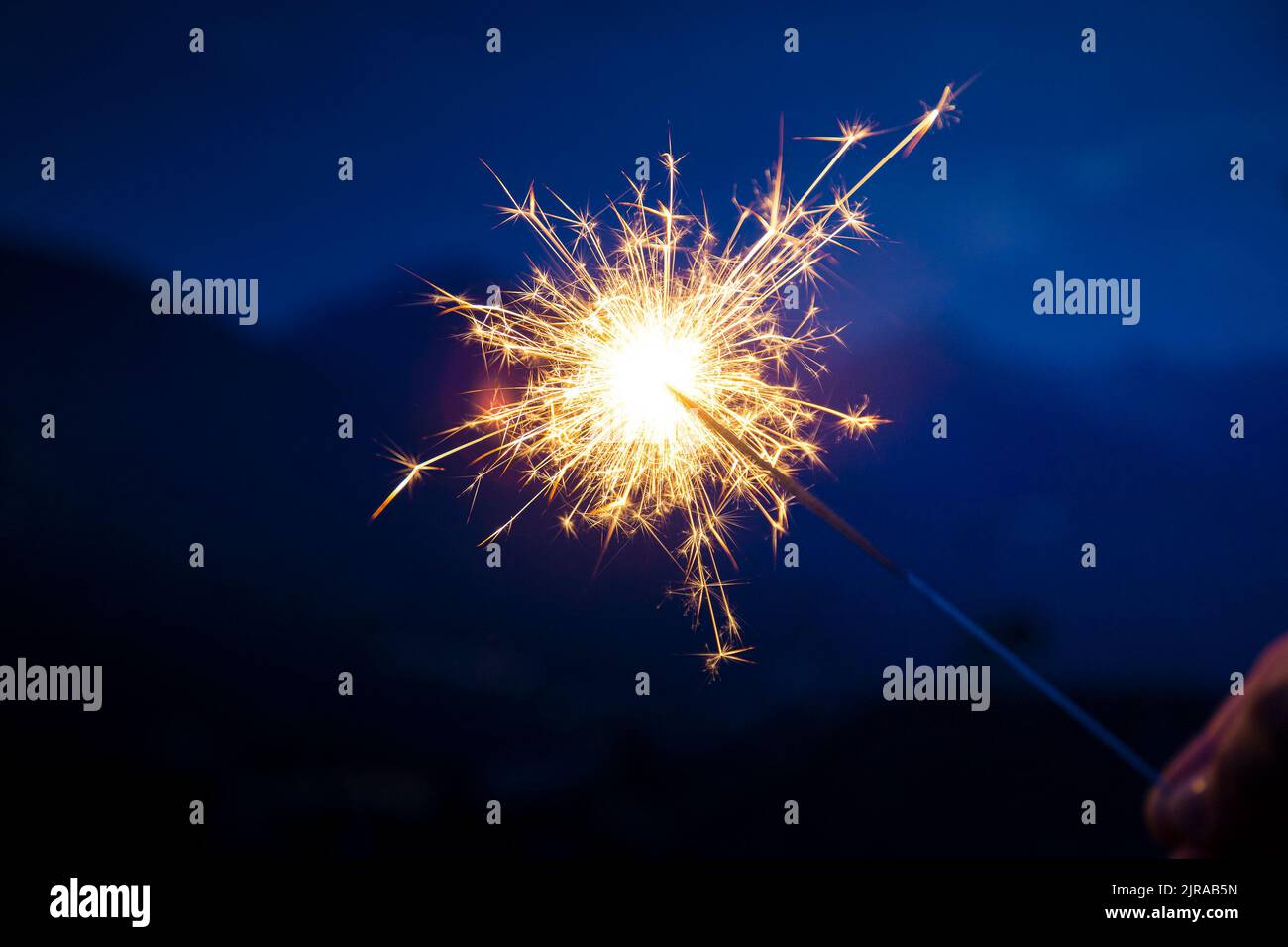 Hand holding a sparkler, or bengal fire stick, burning in outdoor ...