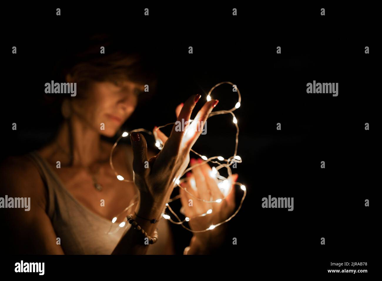 Beautiful caucasian woman, blurred face, holding string lights in the ...