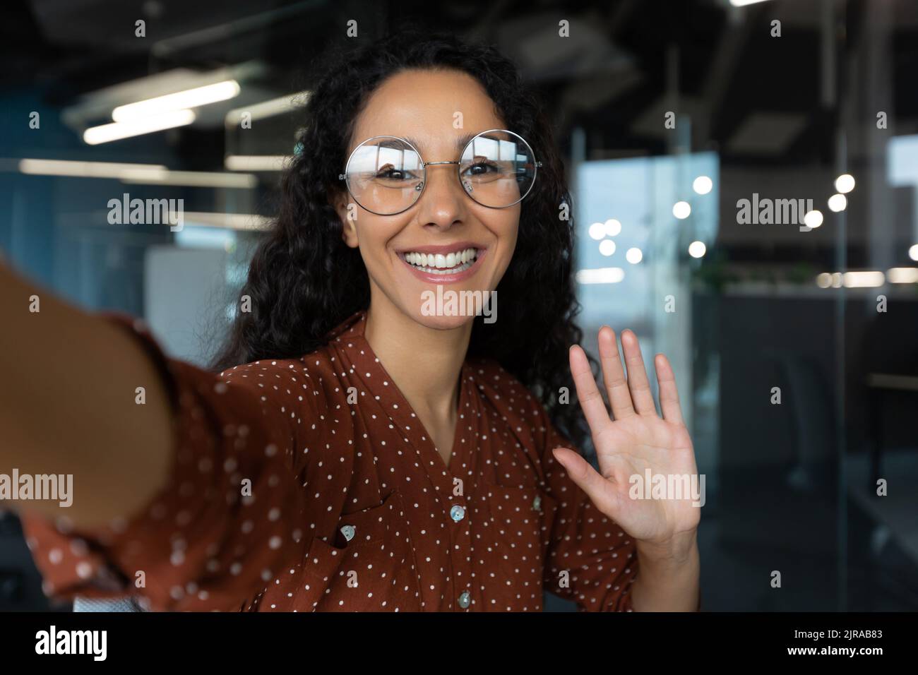 Beautiful Business Woman With Curly Hair Wearing Looking At Smartphone Camera Waving Her Hand