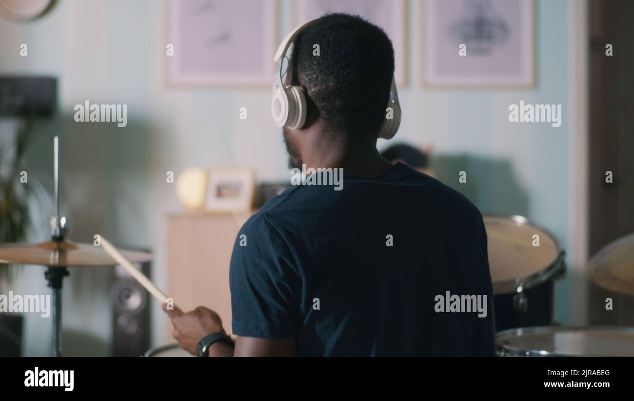 Back view of African American musician in headphones playing drums ...