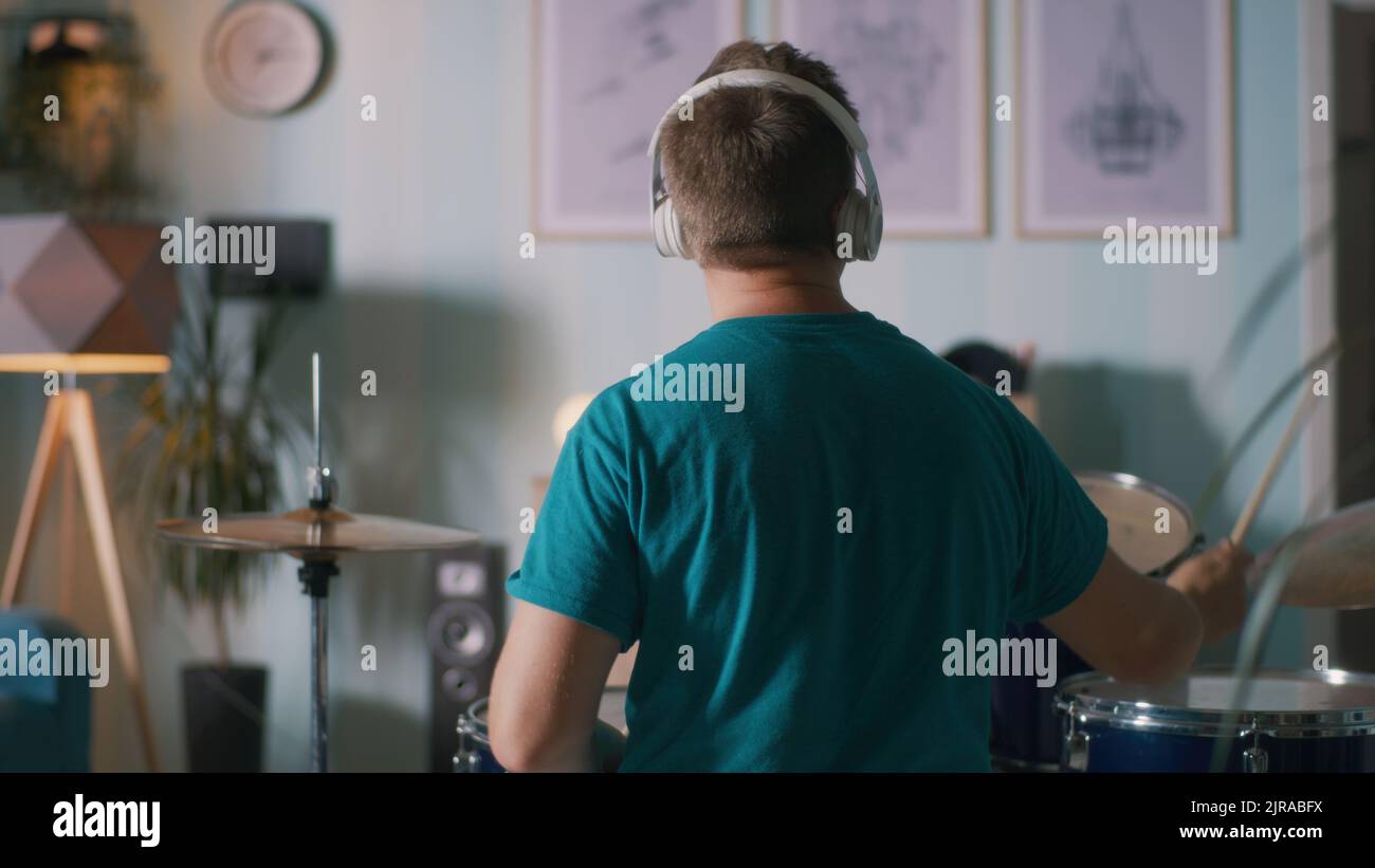 Back view of man in blue t shirt listening to music in wireless ...