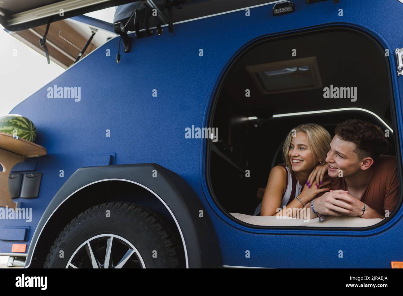 Happy young couple lying together in a van, enjoying vacation time ...