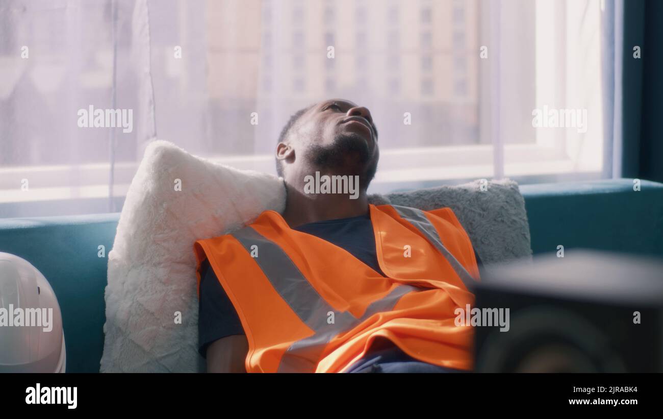 Exhausted black man in vest waking up and putting on hardhat then ...