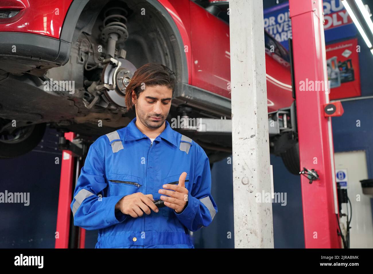 Male car operator wearing blue overalls,cap and gloves working under ...