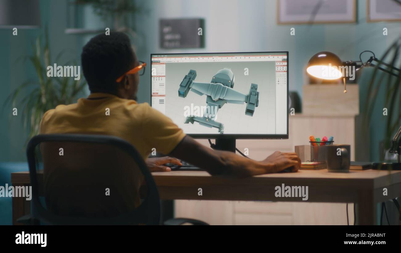 Black man using computer and creating 3D model of futuristic aircraft for videogame or movie ...