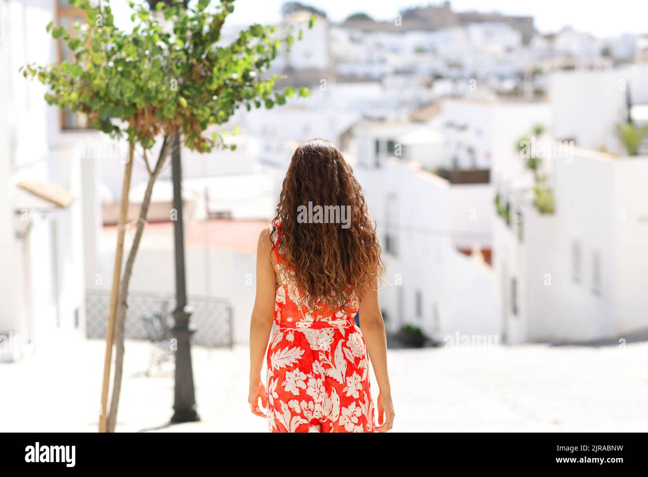 Back view of a tourist walking in a town street on summer vacation ...